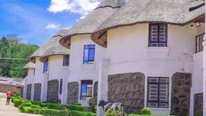 Uma fileira de casas de campo tradicionais com telhados de palha, paredes de pedra e janelas.