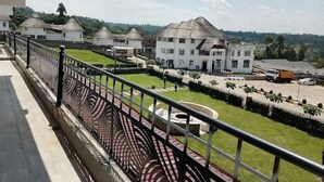 Vista de um pátio com edifícios, área pavimentada e grade de metal.