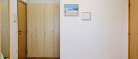 Um corredor com portas de madeira, um quadro na parede e uma cadeira no canto.