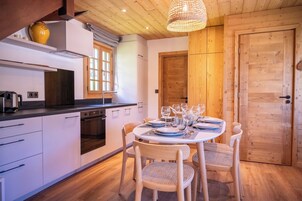 Cozinha moderna com armários brancos, uma mesa de jantar posta para quatro e uma porta de madeira.