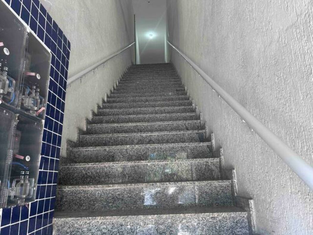 Uma escadaria com corrimão, conduzindo a uma luz no topo.