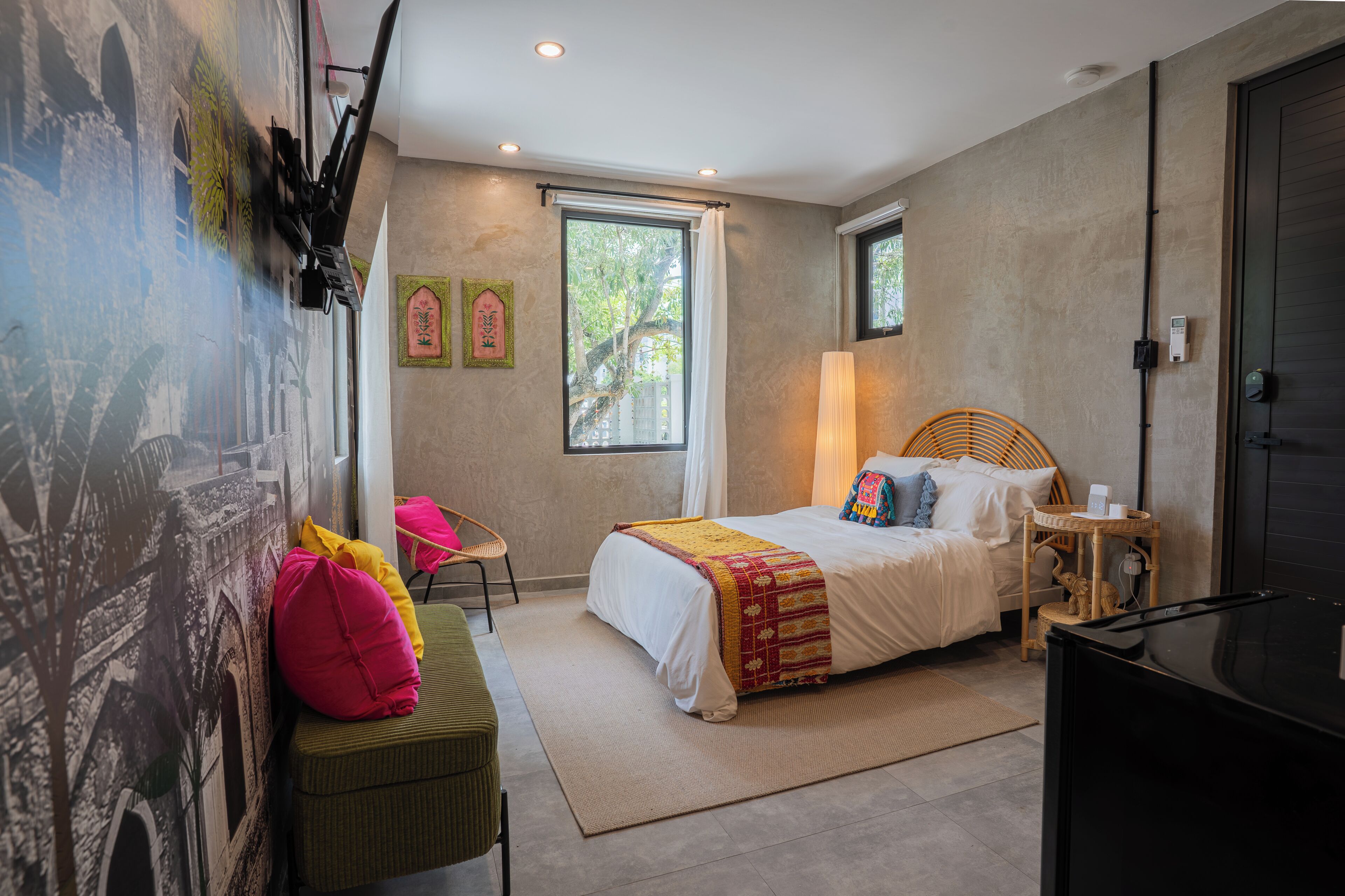 Um quarto com uma cama, uma cadeira, uma escrivaninha, um abajur e uma janela.