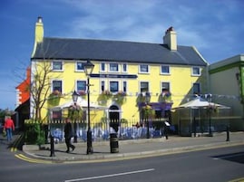 Um edifício amarelo com uma placa que diz 'The Queen's Arms'.