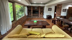 Sala de estar com lareira de tijolos, um sofá, uma mesa de madeira e uma televisão.
