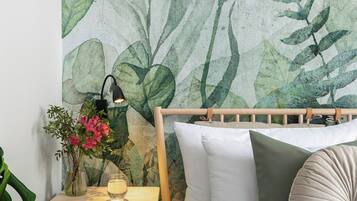 Quarto com cama, mesa de cabeceira, abajur e parede com padrão de folhas.