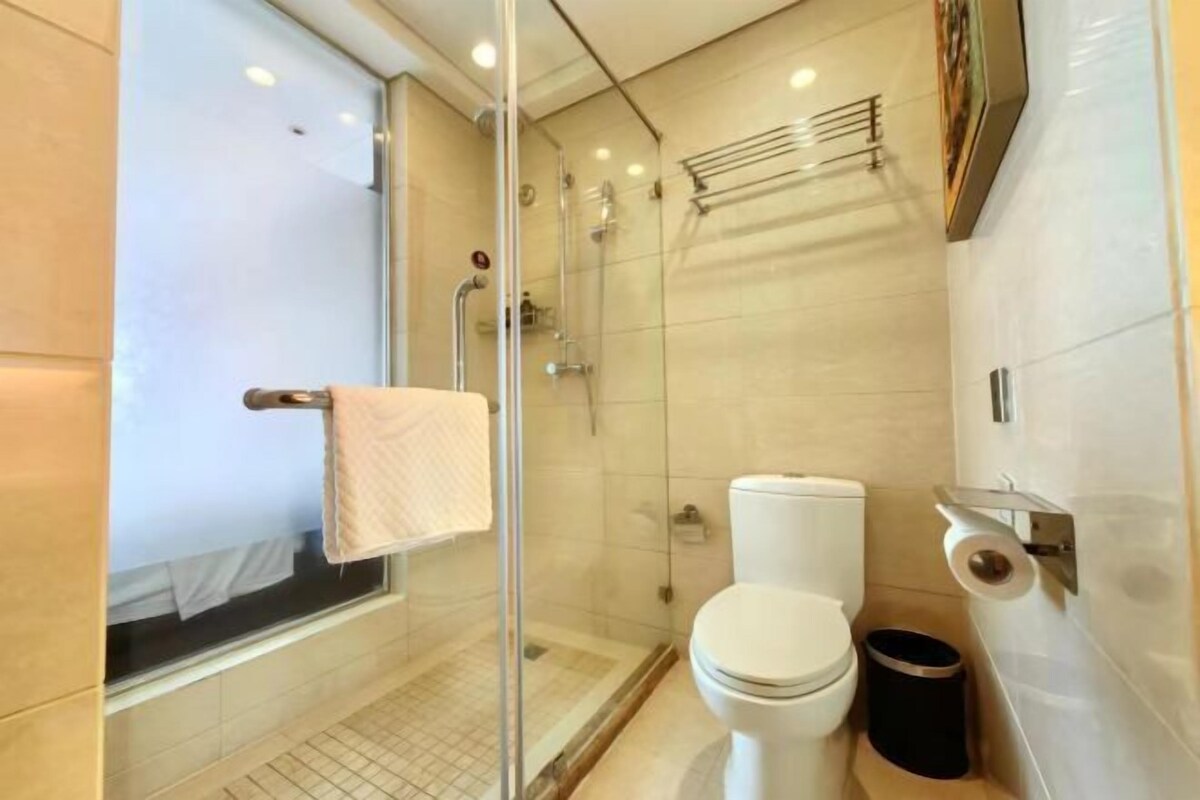 Uma casa de banho moderna com chuveiro em cabine de vidro, sanita e suporte para toalhas.