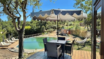 Um deck de madeira com piscina, espreguiçadeiras e uma mesa com cadeiras.