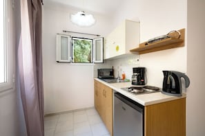 Uma cozinha compacta com lava-louças, cafeteira e chaleira no balcão.