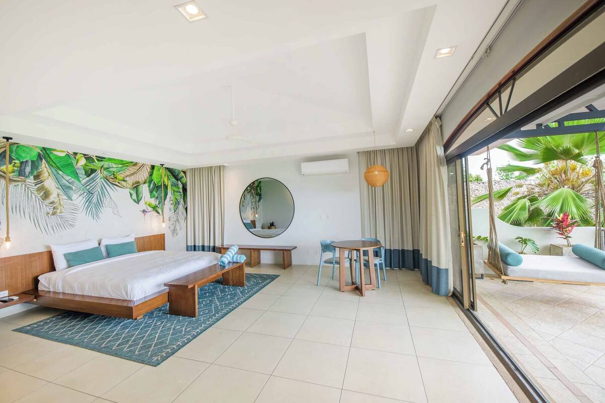 Quarto de hotel moderno com uma cama grande, uma mesa e um espaço de estar.