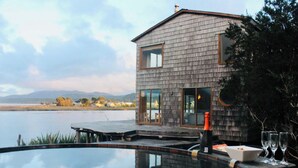 Uma casa moderna com uma grande janela de vidro, piscina e deck de madeira.