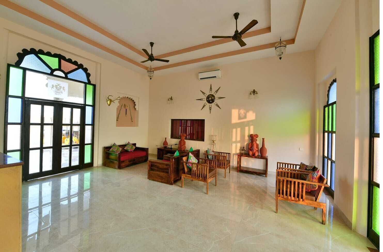 Uma sala de estar espaçosa com teto alto, ventiladores e uma grande janela com moldura decorativa, e um sofá vermelho.