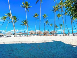 Uma praia com palmeiras e guarda-sóis de palha.
