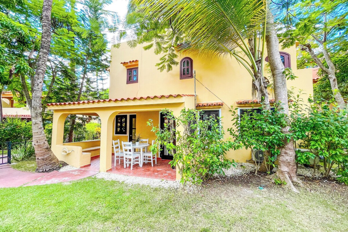 Um edifício amarelo com um pátio, uma mesa e cadeiras.