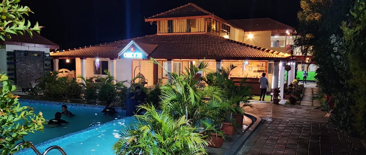 Um resort com piscina, um edifício bem iluminado e um calçadão pavimentado.