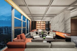 Um lounge moderno com vista para a cidade, assentos confortáveis e uma lareira.