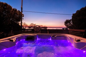 Uma banheira de hidromassagem com um volante de controle, rodeada por uma cerca, com vista para o pôr do sol ao fundo.