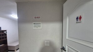 Um corredor com uma porta branca, uma placa indicando área para fumantes e um sinal de banheiro.