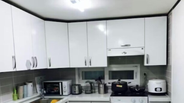 Uma cozinha compacta com armários brancos, máquina de lavar, micro-ondas e fogão.