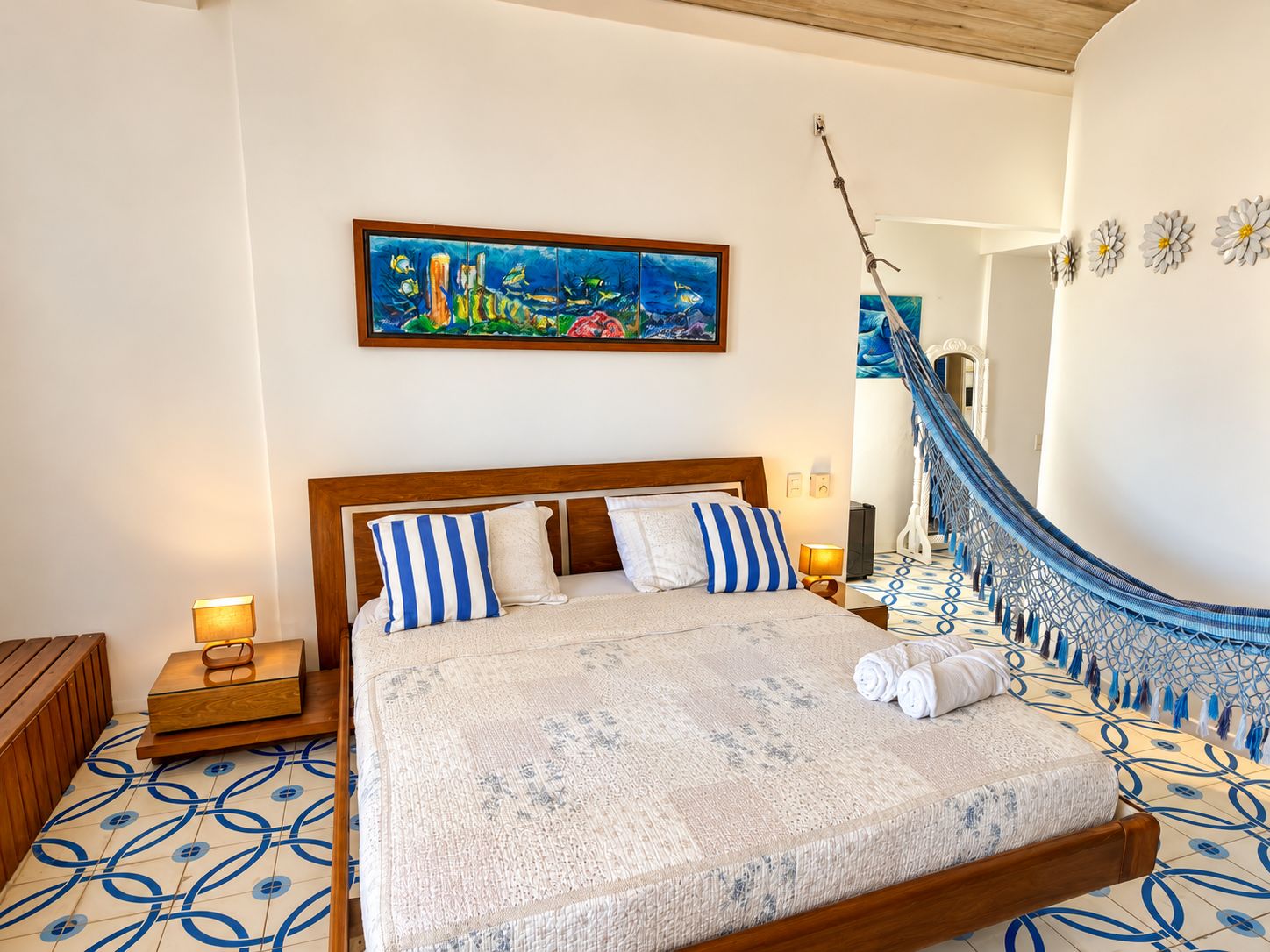 Quarto de hotel com cama, rede, um quadro e chão estampado.