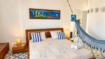 Quarto de hotel com cama, rede, um quadro e chão estampado.