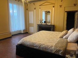 Quarto com uma cama grande, penteadeira, espelho e lareira.