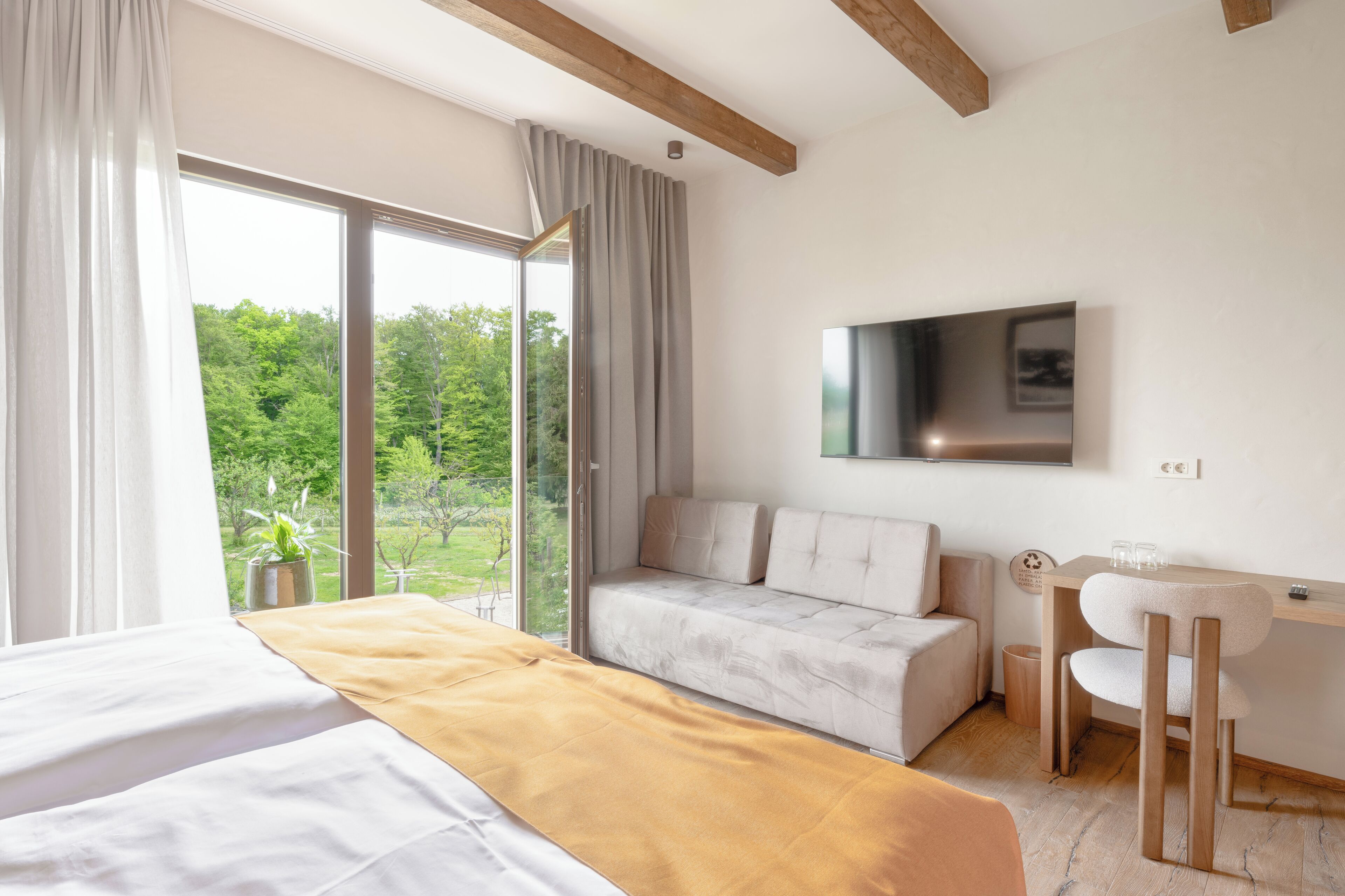 Um quarto moderno com uma cama grande, um sofá, uma escrivaninha e uma televisão.