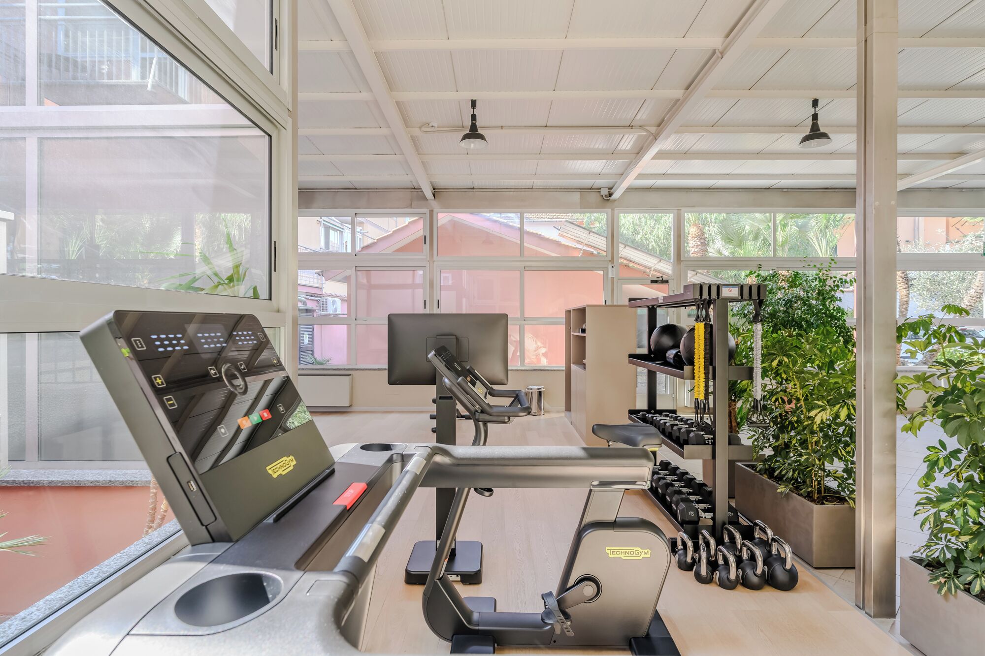 Uma academia com equipamentos de cardio, halteres e esteira.