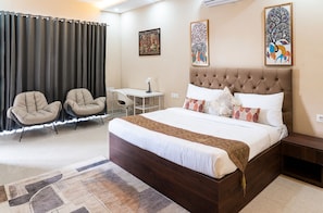 Quarto com uma cama grande, duas poltronas, uma escrivaninha e uma cadeira.