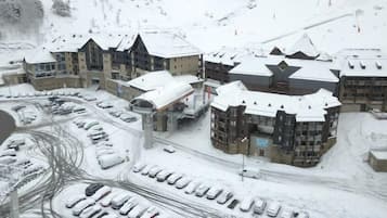 Estância de esqui coberta de neve com vários edifícios, um parque de estacionamento e um teleférico.