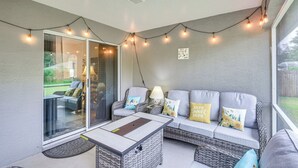 Uma varanda coberta com área de estar, luzinhas e vista para o exterior.