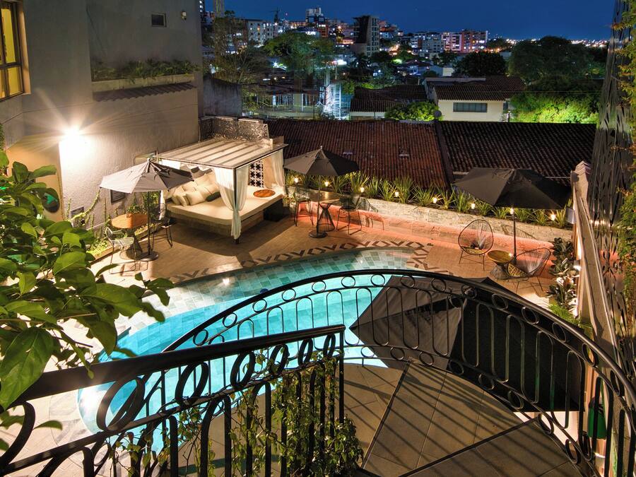 Uma área de piscina no terraço, com espreguiçadeira, um espaço para sentar e uma escadaria que dá para um andar superior.