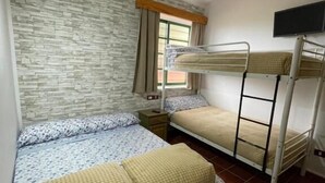 Quarto de dormitório com duas beliches, parede com padrão de pedra, janela com cortinas e televisão fixada na parede.