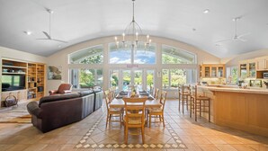 Uma cozinha espaçosa com uma bancada grande, uma área de jantar com vista para o exterior, e uma sala de estar aconchegante com lareira.