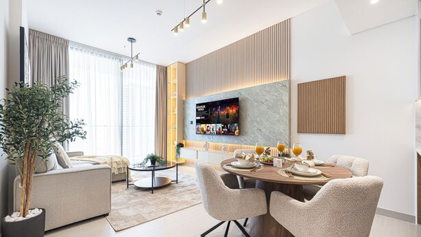 Uma sala de estar moderna com sofá, mesa de jantar, cadeiras e uma TV fixada na parede.