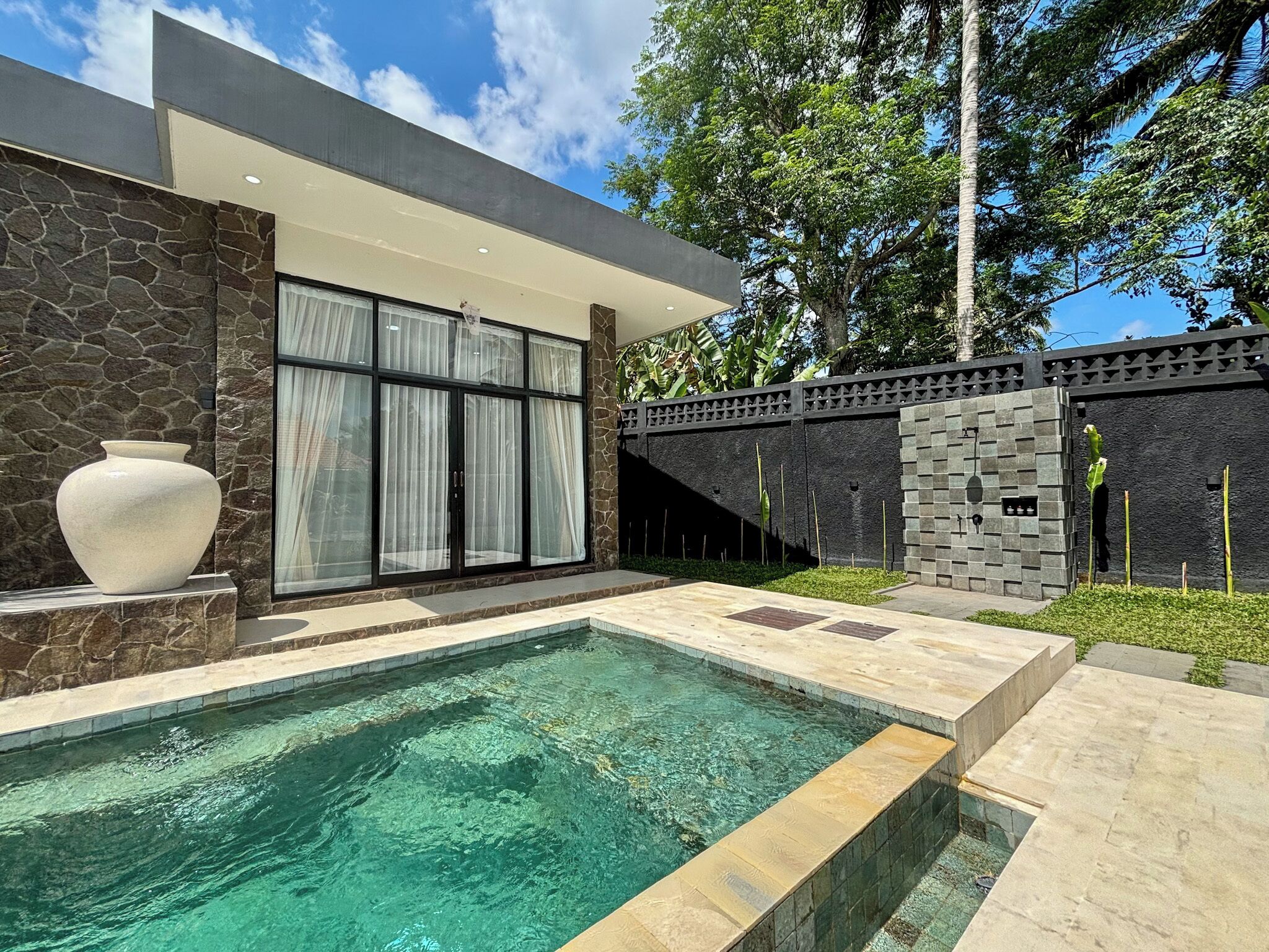 Uma área de piscina moderna ao ar livre, com paredes de pedra e uma grande janela.