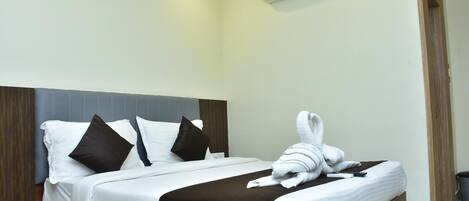 Quarto de hotel com cama, cabeceira, ar-condicionado fixado na parede e porta de madeira.