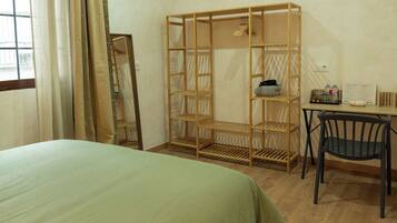 Quarto com cama, estante de madeira, escrivaninha com cadeira e janela com cortinas.