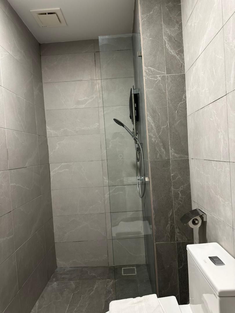 Um banheiro moderno com chuveiro em gabinete de vidro, ladrilhos de mármore e vaso sanitário branco.