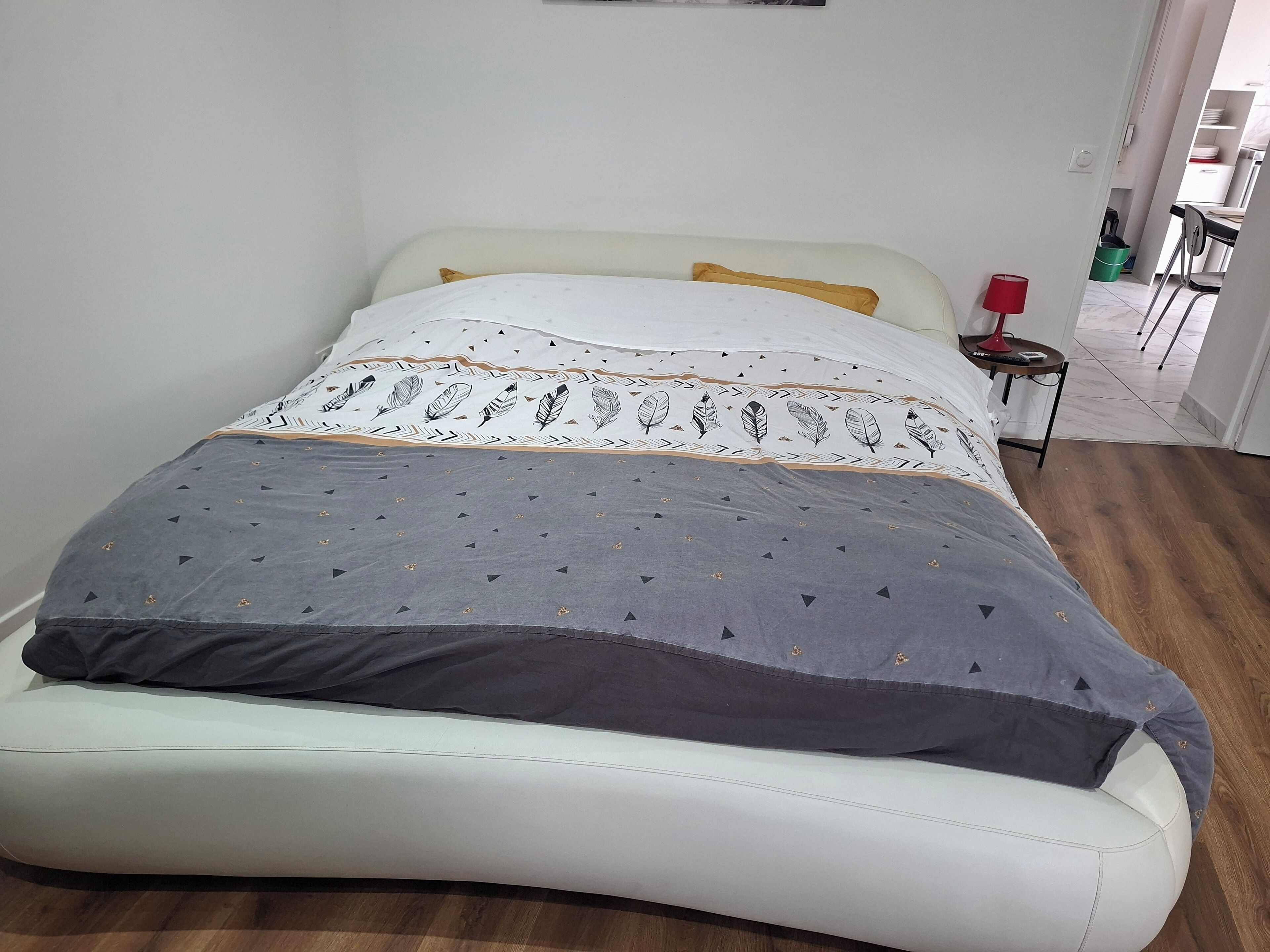 Uma cama com colcha estampada, um travesseiro e uma mesa de cabeceira com abajur.