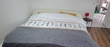 Uma cama com colcha estampada, um travesseiro e uma mesa de cabeceira com abajur.