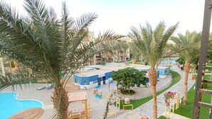 Um resort com piscina, palmeiras e área de recreação infantil.
