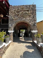 Fachada de pedra com o texto "Cosala Grand Boutique Resort Spa" e um arco que dá acesso à entrada.
