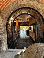Entrada para um resort boutique com um arco de pedra, um candelabro e uma piscina visível ao fundo.