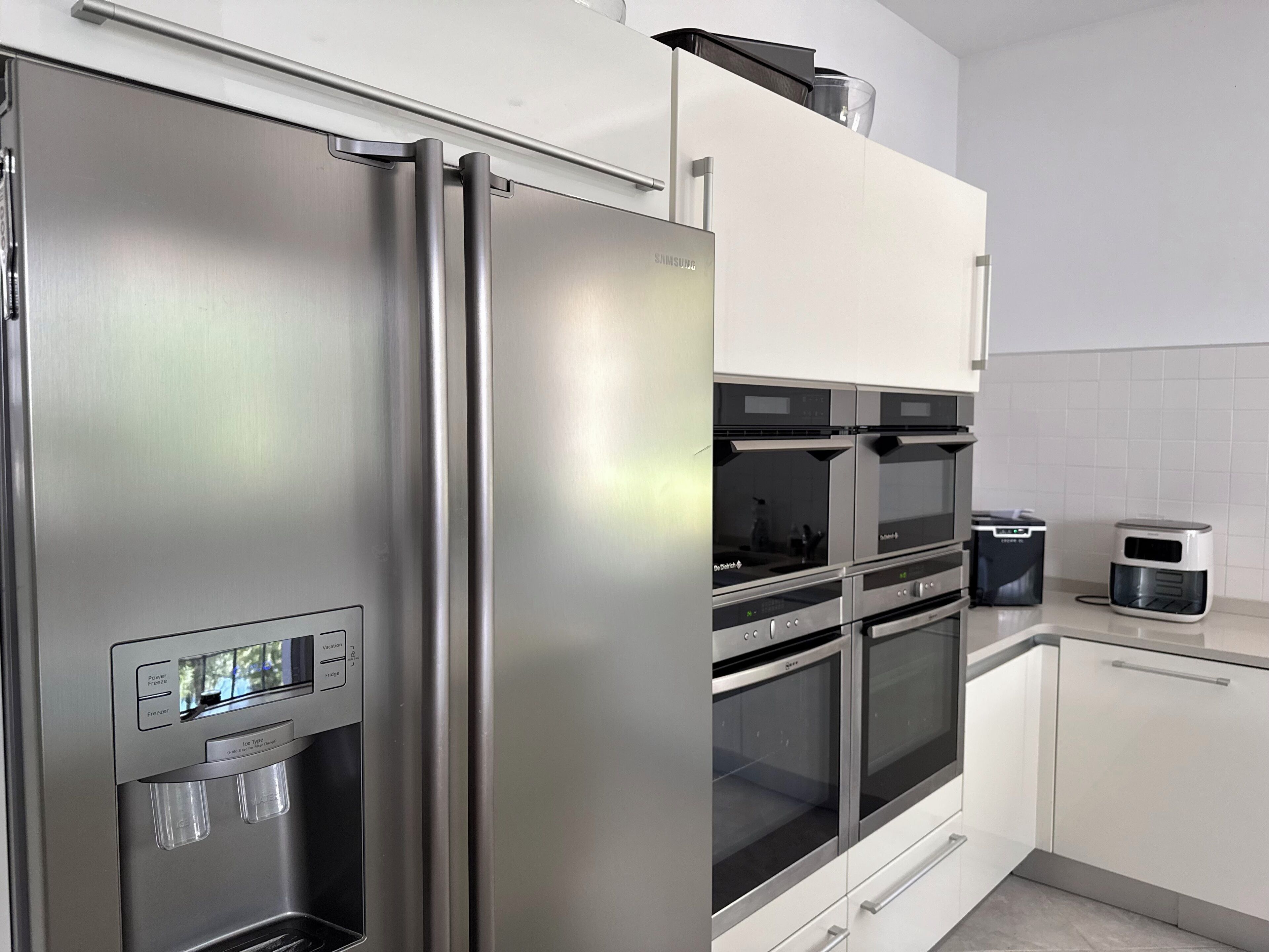 Uma geladeira de aço inoxidável com dispensador de água, forno embutido e micro-ondas.