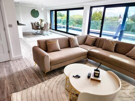 Uma sala de estar moderna com um sofá seccional, uma mesa de centro redonda e um espaço de jantar com mesa e cadeiras.