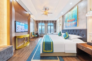 Quarto de hotel com uma cama grande, televisão, escrivaninha e vista da cidade.