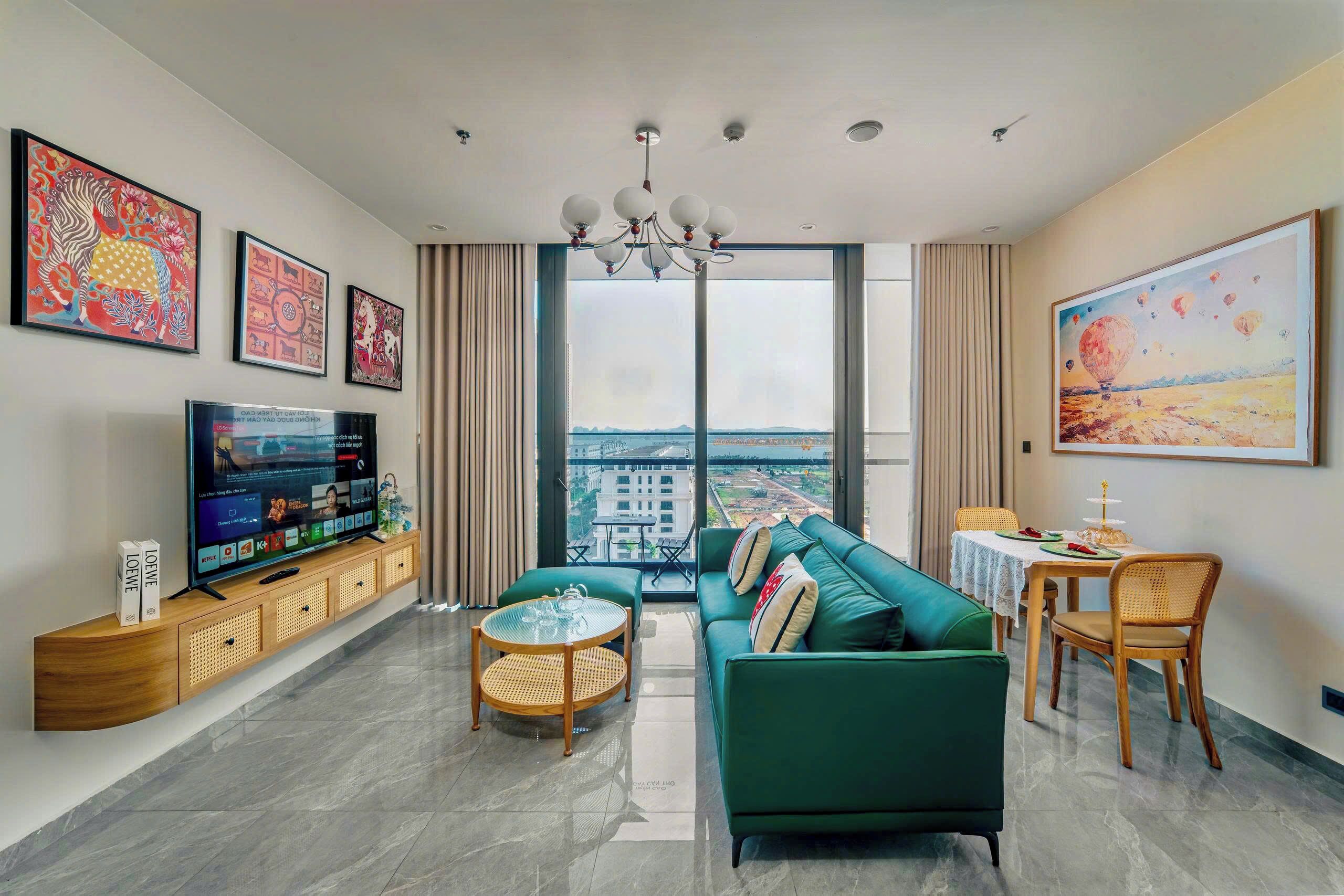 Uma sala de estar moderna com um sofá verde, uma mesa de jantar e uma TV sobre um console de madeira.
