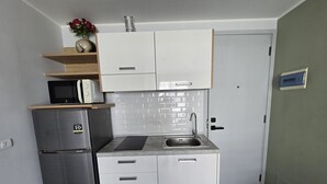Uma cozinha compacta com armários brancos, geladeira de aço inoxidável, micro-ondas e pia.