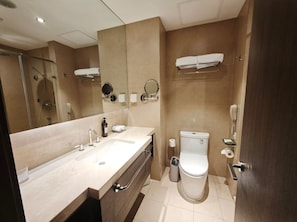 Uma casa de banho moderna com um espelho grande, duas pias, sanita e chuveiro.