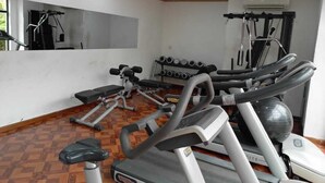 Uma academia com esteiras, aparelhos de musculação e um espelho grande.